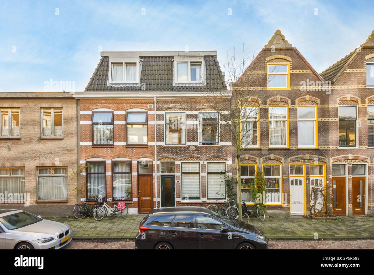 some houses with cars parked on the street in front of them and one car ...