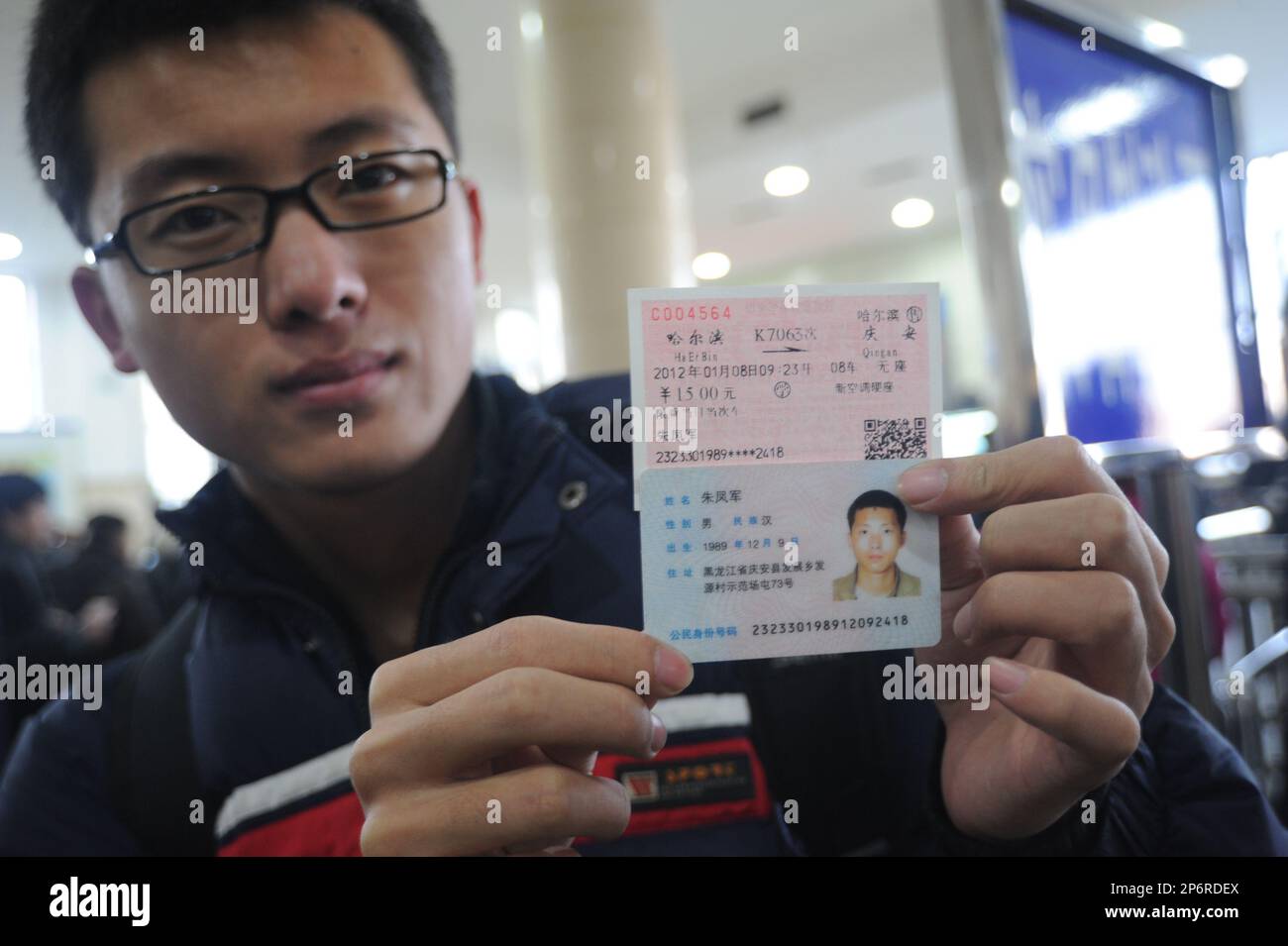 A young man sitting in the waiting room with his train ticket and ...