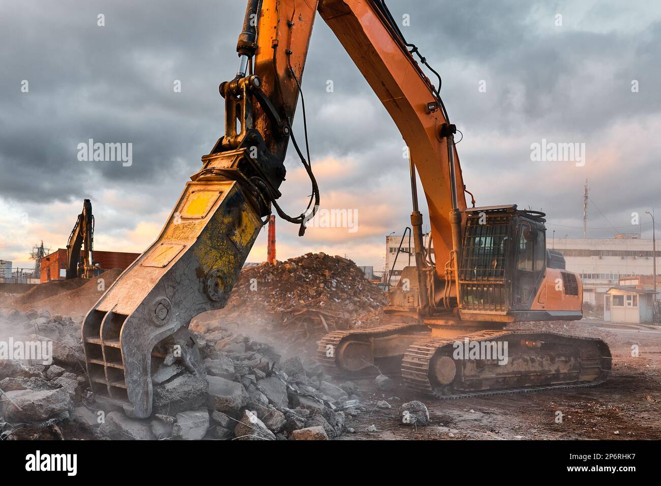 Excavator with concrete crusher at demolition site Stock Photo - Alamy