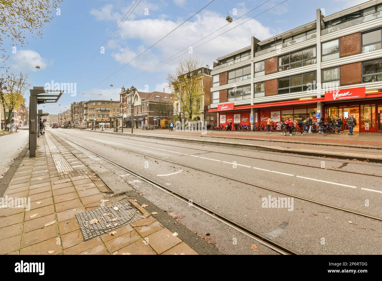 an empty city street with people walking on the sidewalk and buildings ...