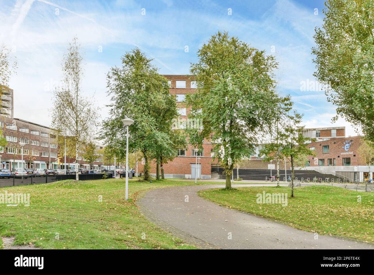 a park with trees and cars parked on the street in front of some tall ...
