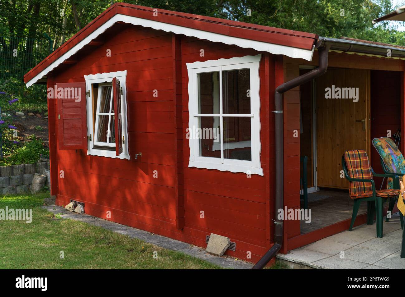 A charming garden shed painted in bright red, with a cozy patio and ...