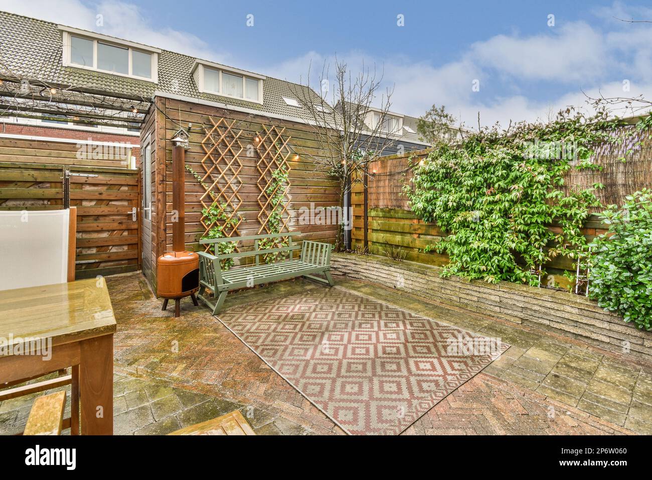 a backyard area with a bench, chair and plants growing on the side of ...