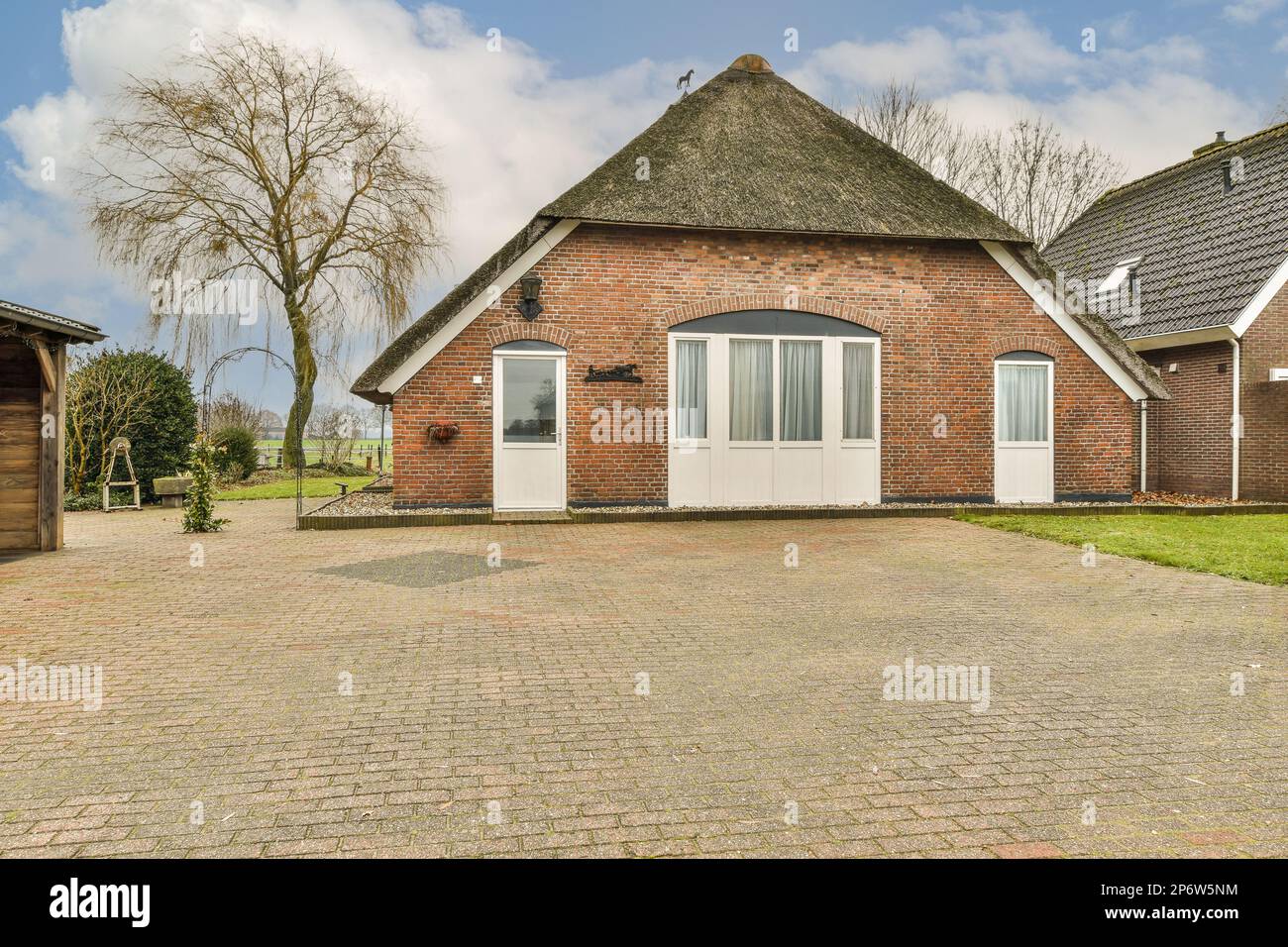 a brick house with a thatched roof and white doors on the front door ...