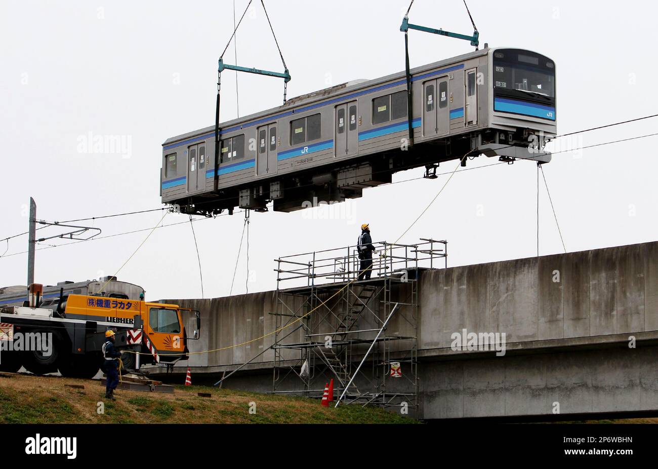 East Japan Railway Co. starts to lift up a stranded train car by a ...