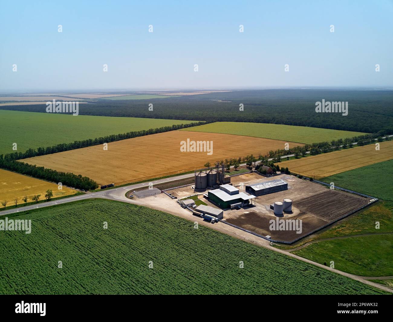Aerial of grain elevator in front of wheat field. Drone photo above flour mill or oil extraction ...