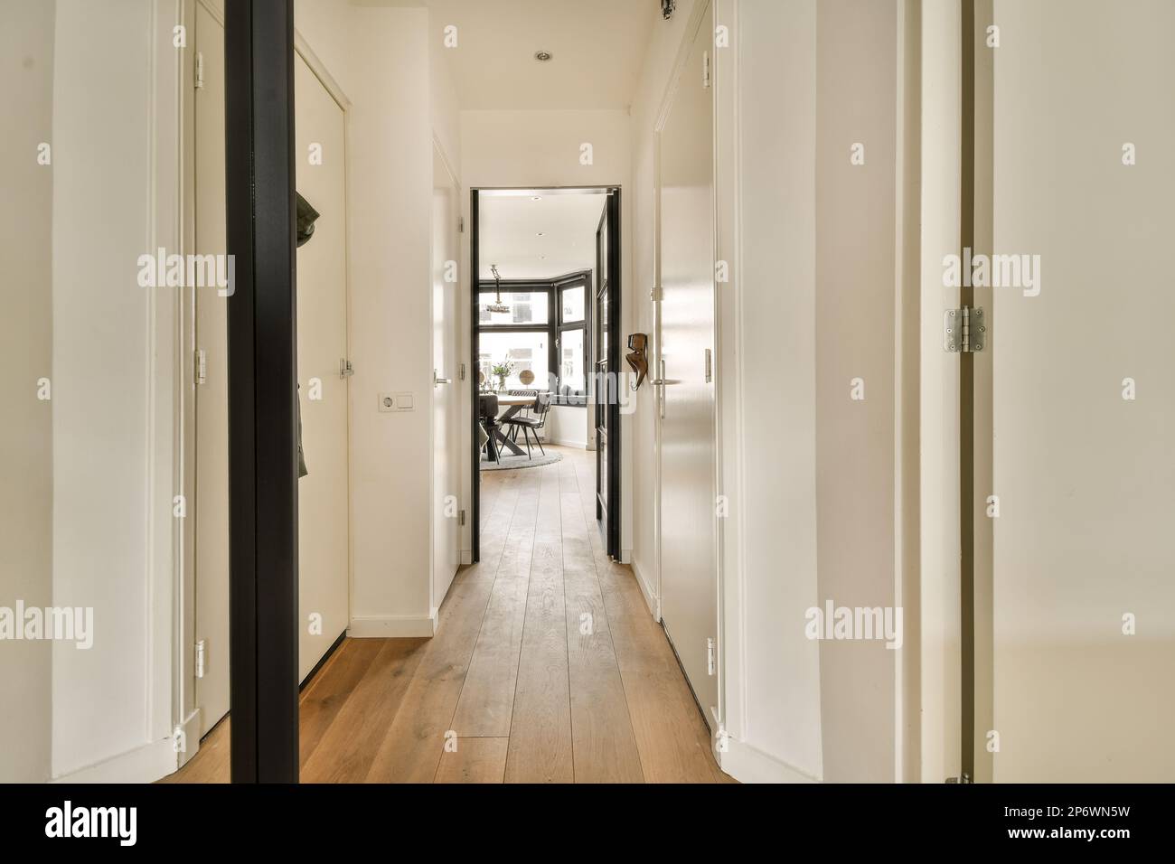 a long narrow hallway with wood flooring and white walls on either side ...