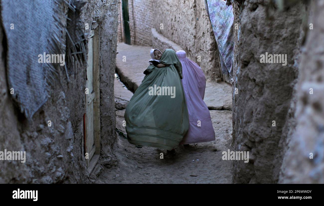 A Pakistani child carried by her mother looks back as they make their ...
