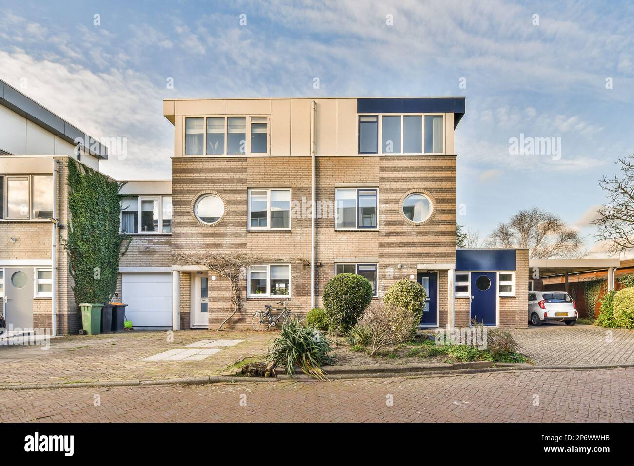 a brick house in the middle of a street with two cars parked on both ...