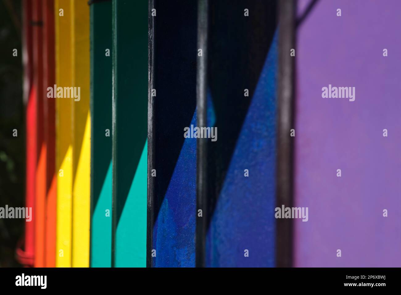 Rainbow colored fence under hard light, parallel vertical lines, and ...