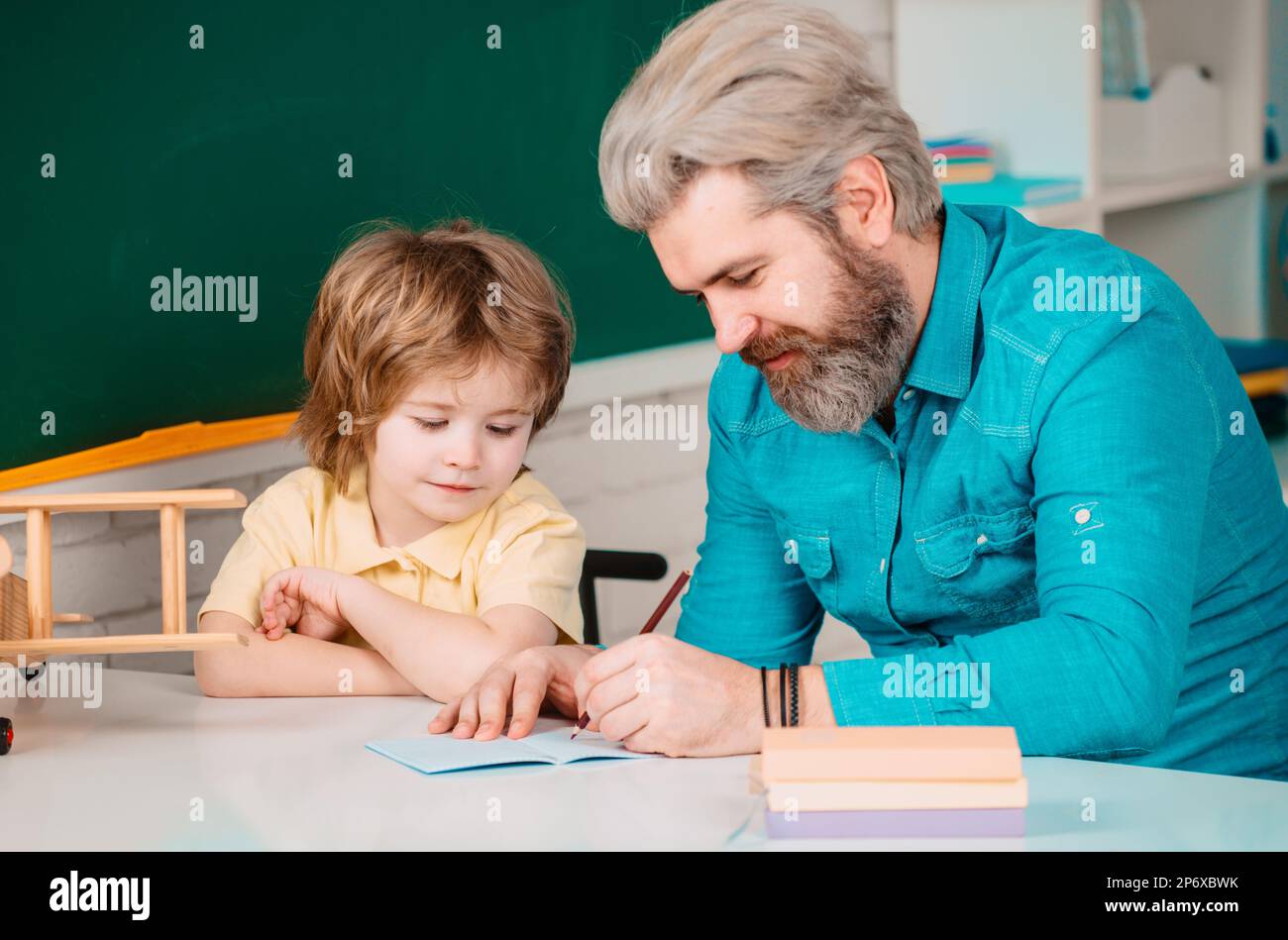 Cute little preschool kid boy with teacher study in a classroom. Young ...