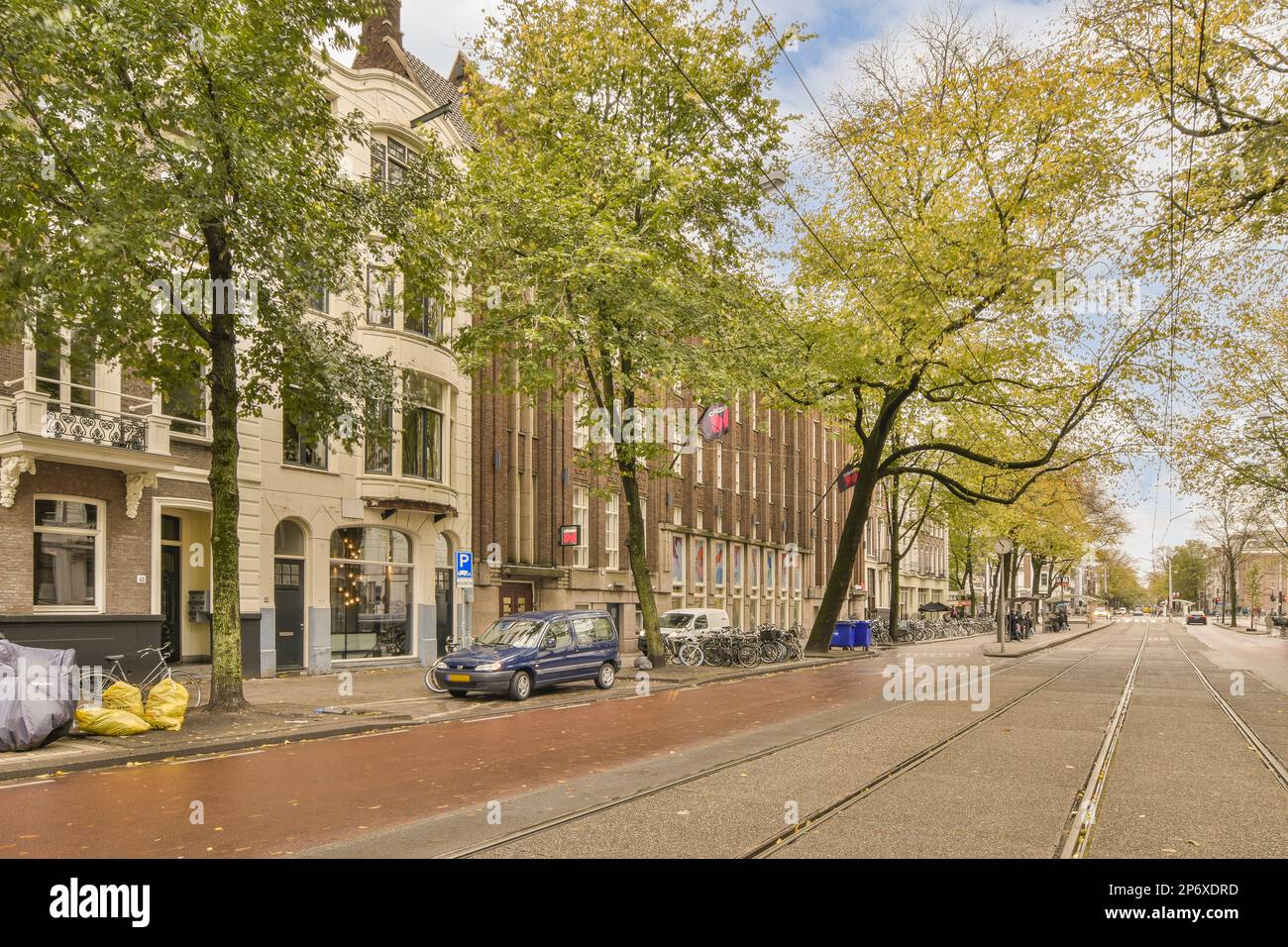a city street with cars parked on the side and trees lining the road in ...