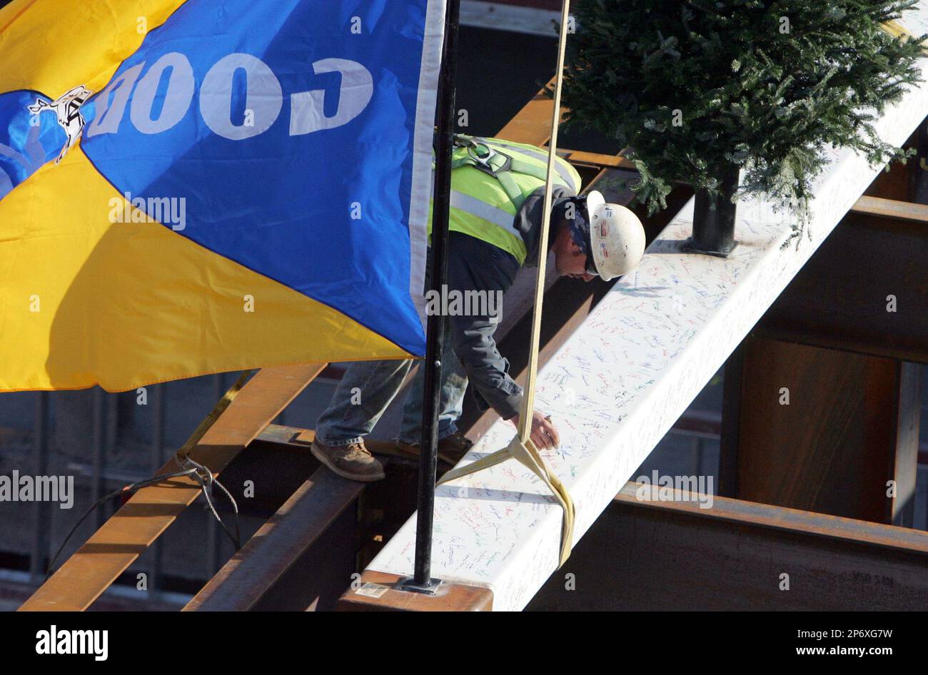 An iron worker installs the final steel beam featuring signatures from ...