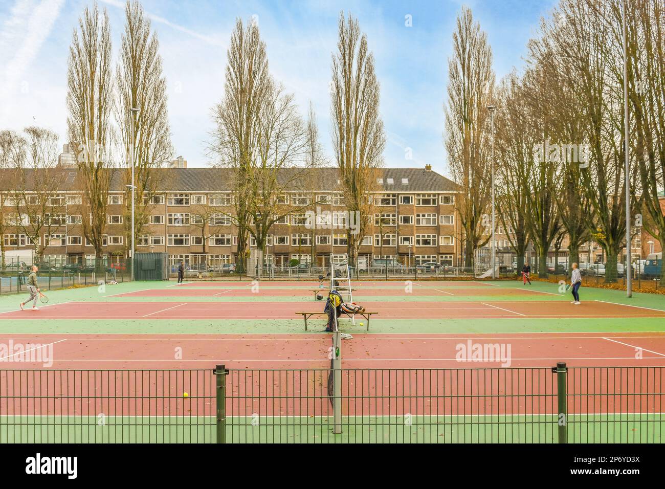 an outdoor tennis court with trees in the background and two people ...
