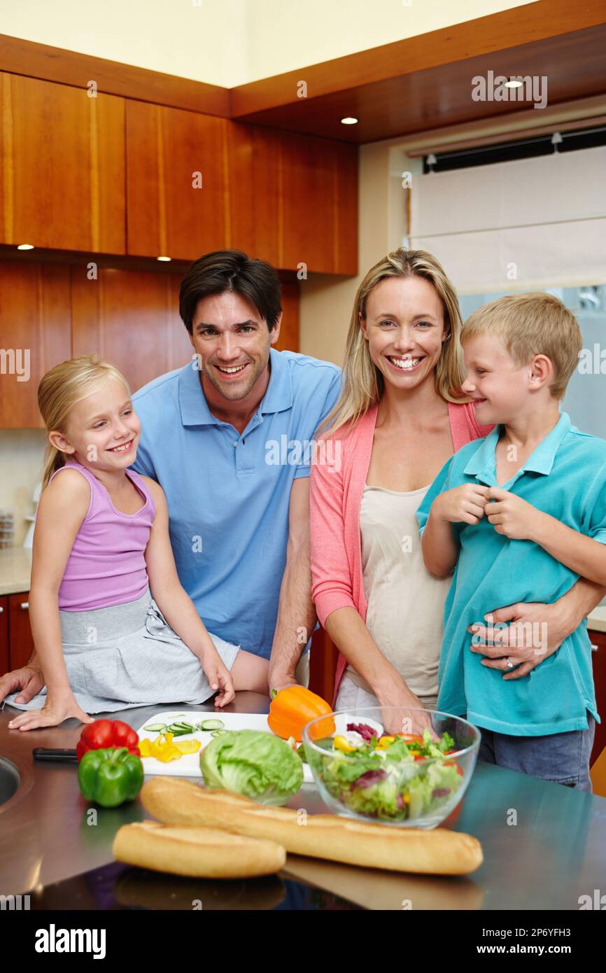 Salad for supper. Portrait of a happy family of four standing behind a ...