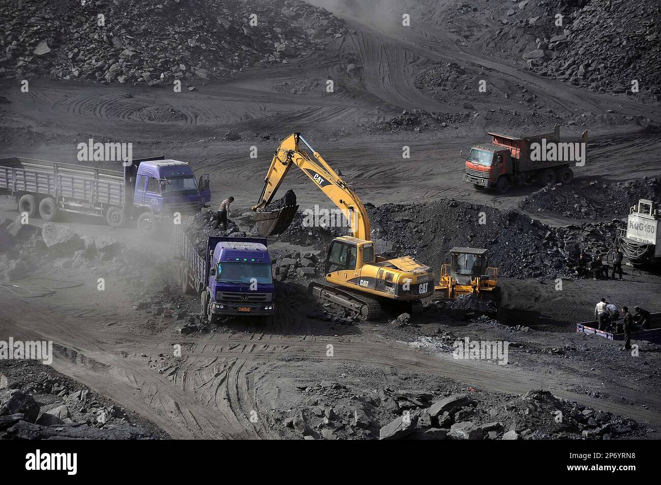 Workers load coal on trucks at the open-air mine of Buya Coal Mine on ...