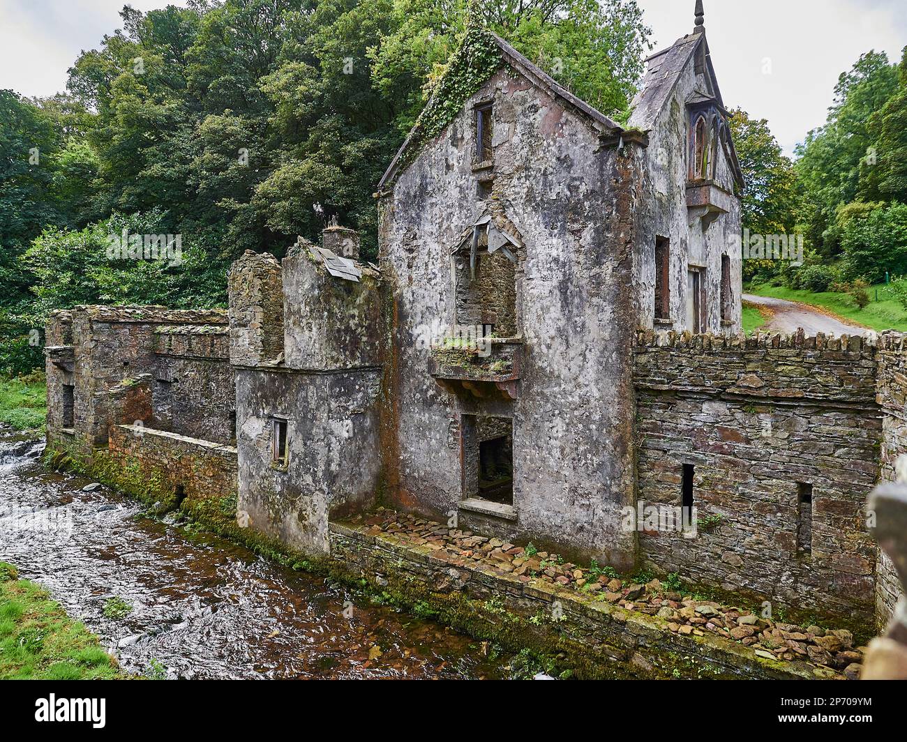 old ruin of an abandoned house along a small river on a rainy day in ...