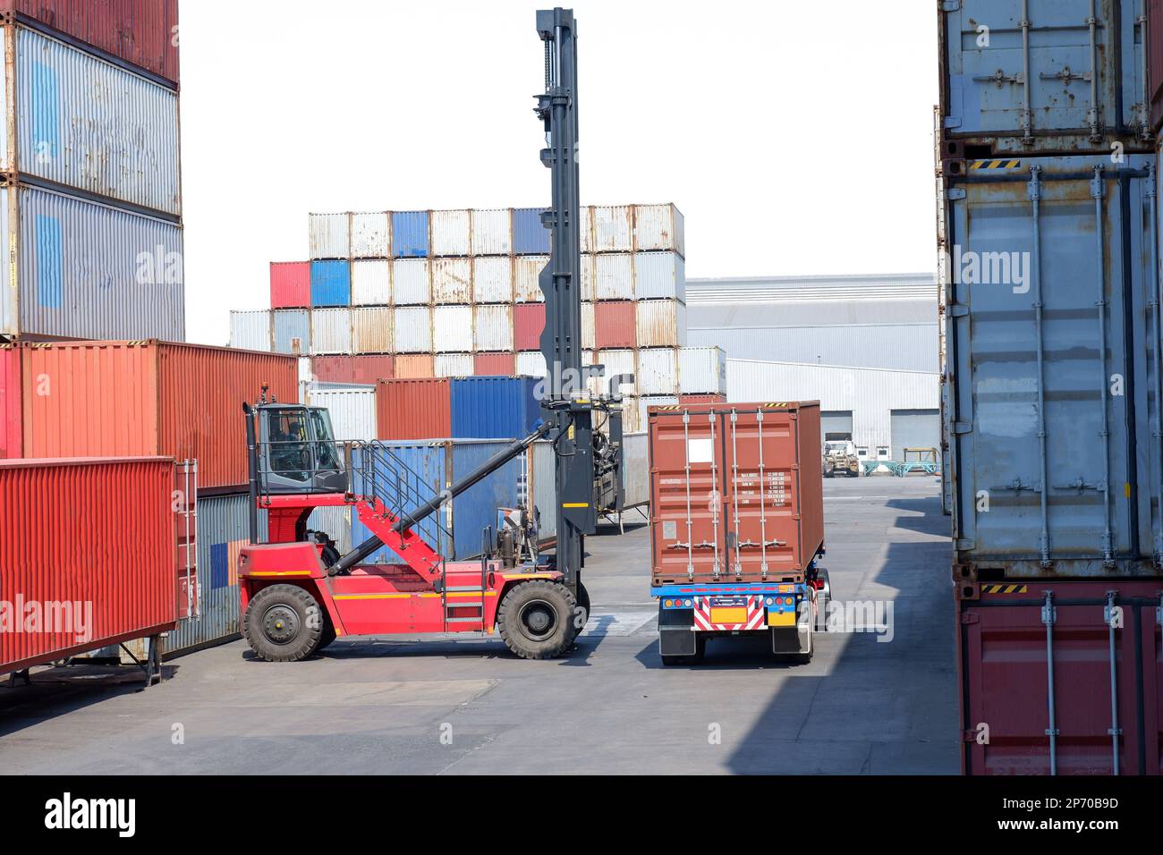 Forklifts lifting containers in shipping yard or pier against sunrise ...