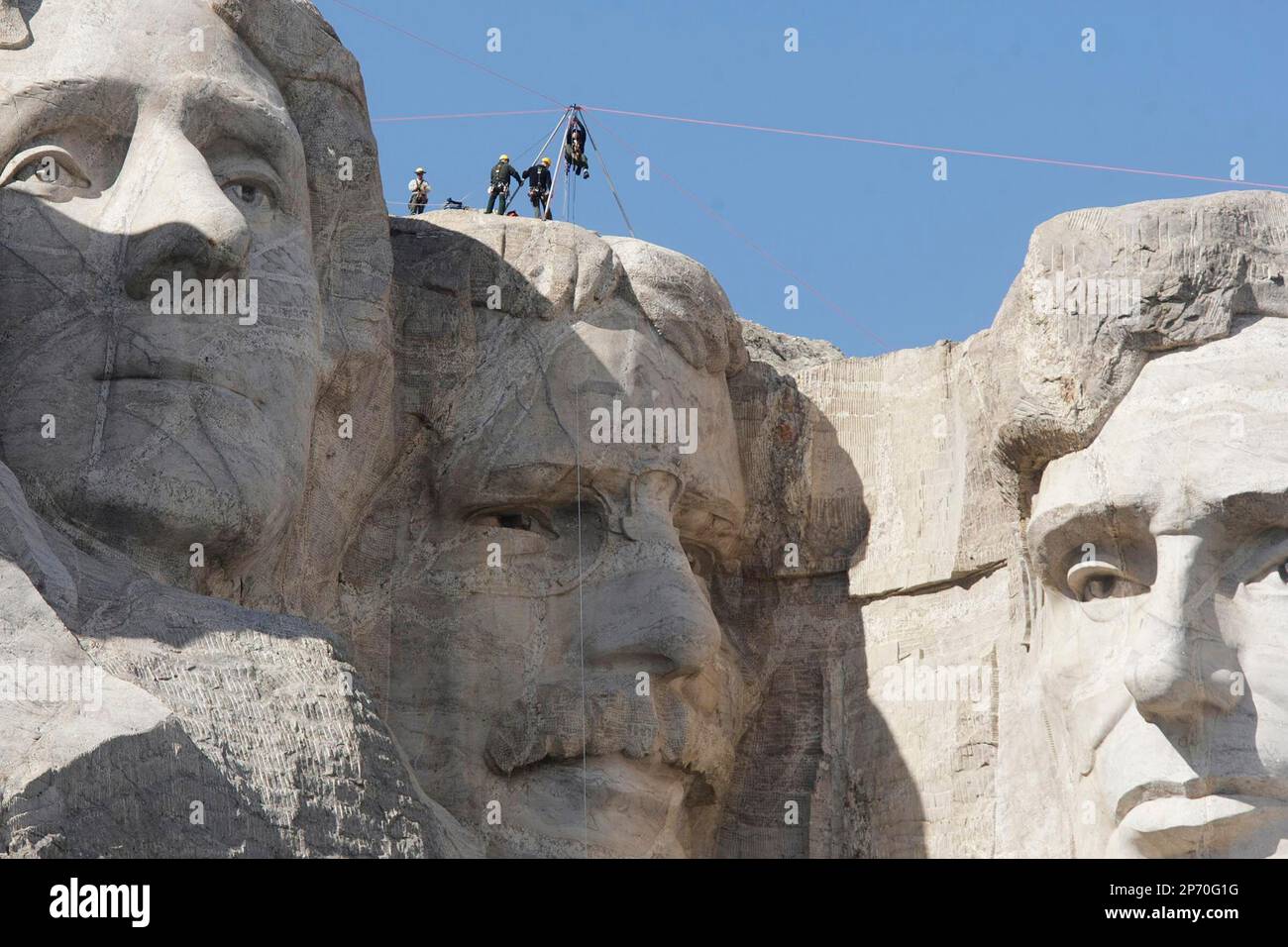 A ropes crew with the Mount Rushmore National Memorial work on top of ...