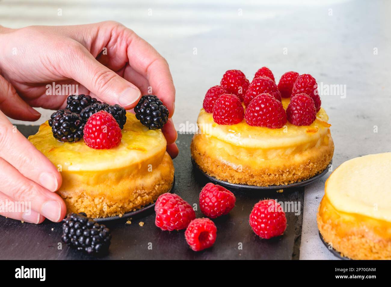Decorating mini cheesecakes with fresh raspberries and blackberries ...