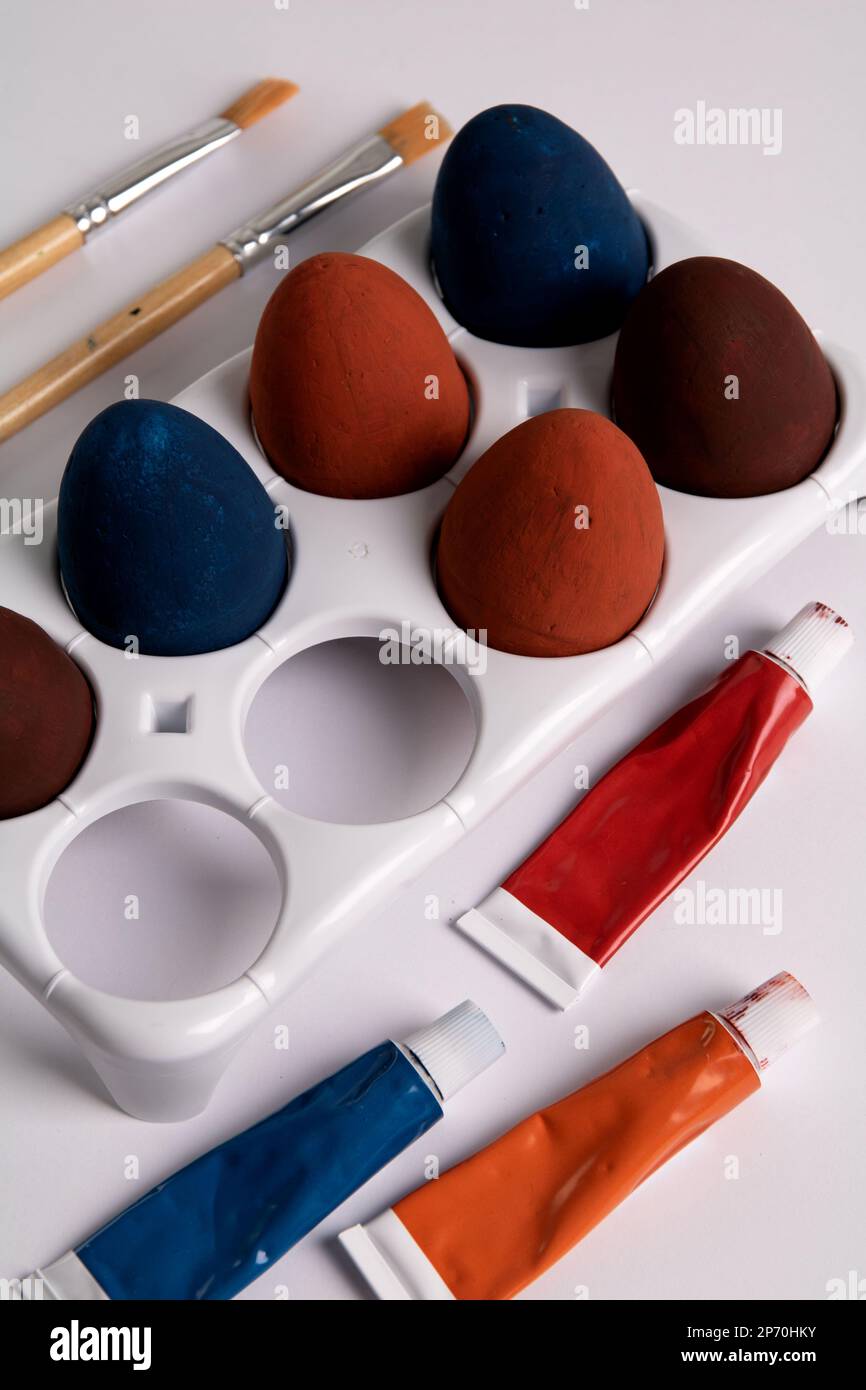 photo of several painted eggs with paints in a tube and brushes on a ...