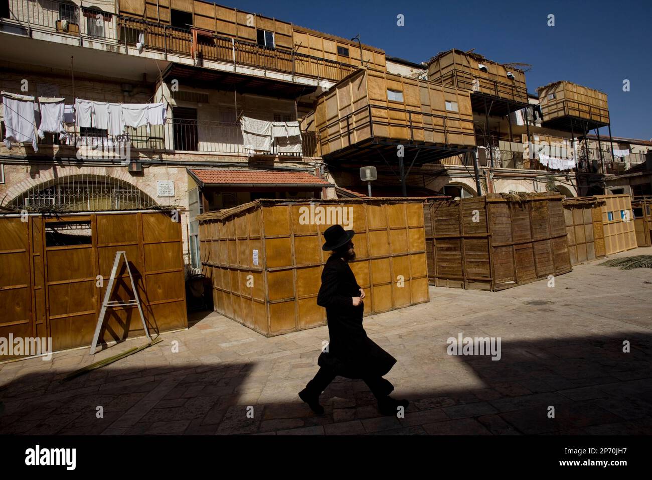 An ultra-orthodox Jewish man walks past Sukkahs, temporary structures ...