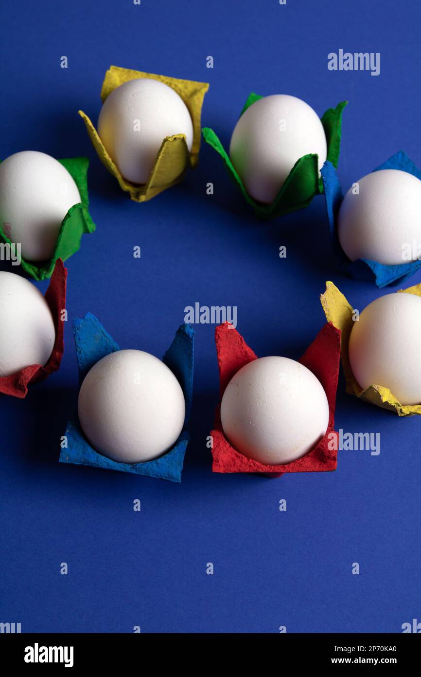 photo a lot of eggs in multi-colored cells stand in a circle on a blue ...