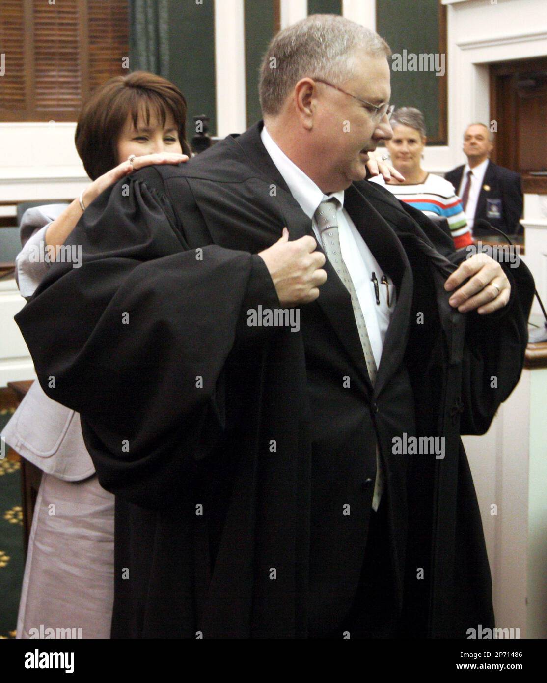 Renee Cain helps her husband Federal Judge Tim Cain put on his robe ...