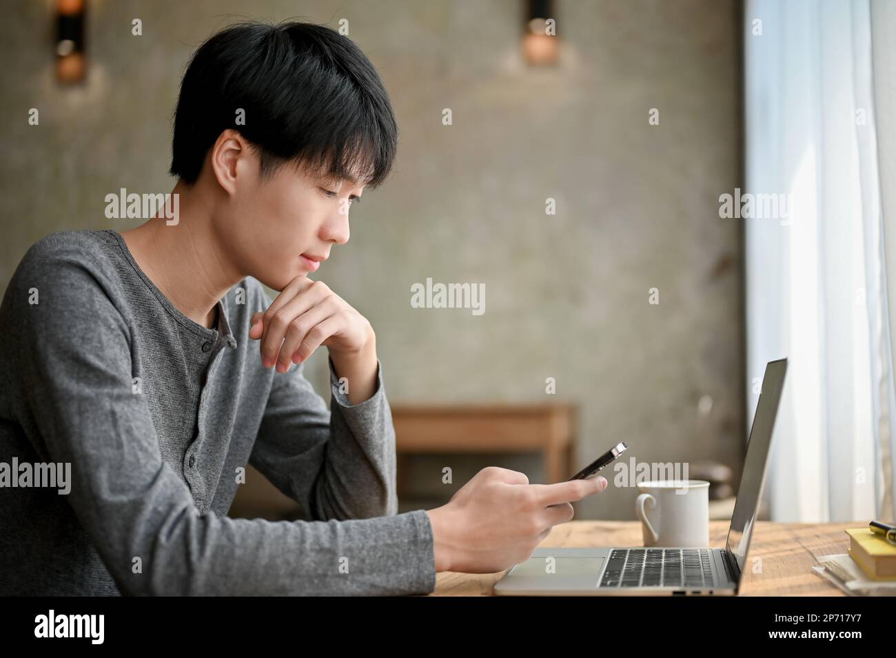 Side view image of thoughtful young Asian male freelancer or college student pensively thinking ...