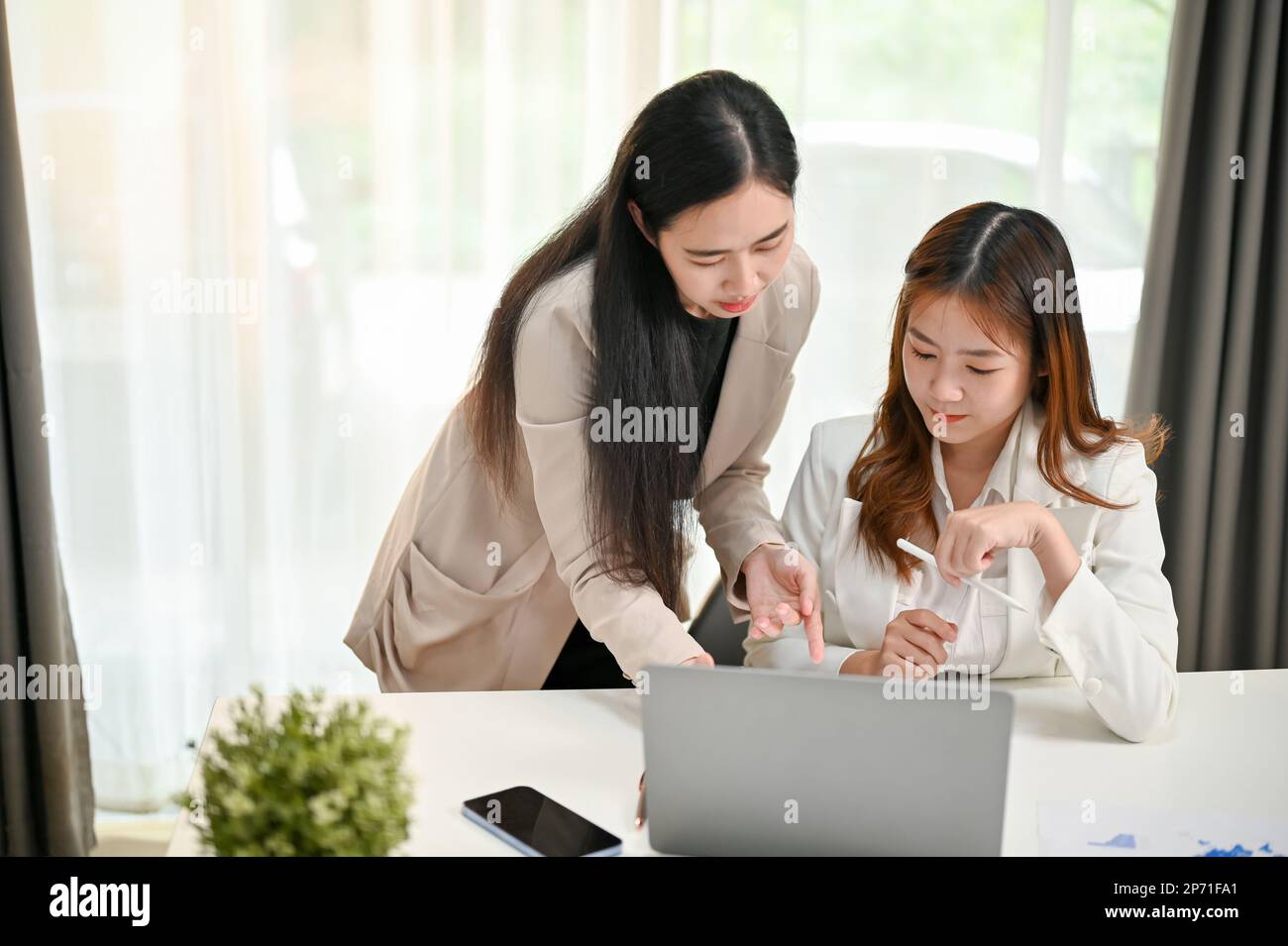 Determined millennial Asian female secretary or assistant talking and ...