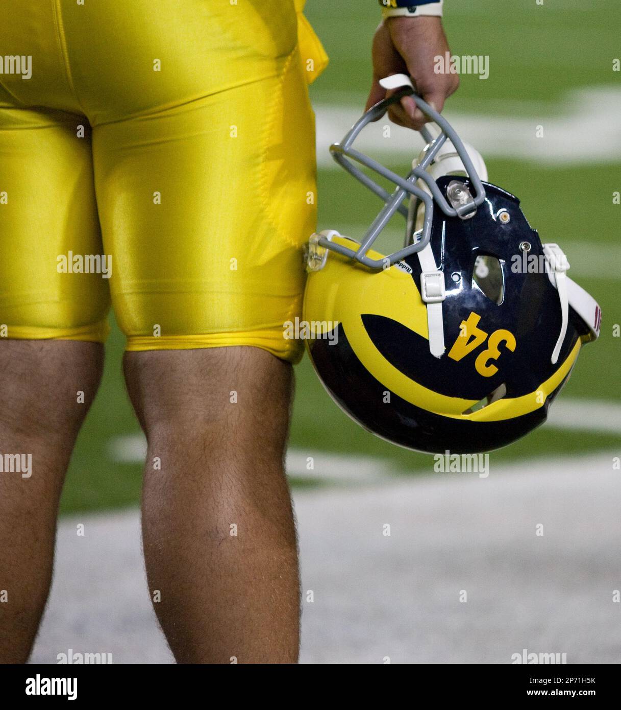 A Michagan Wolverines player holds his helmet on the sidelines while ...