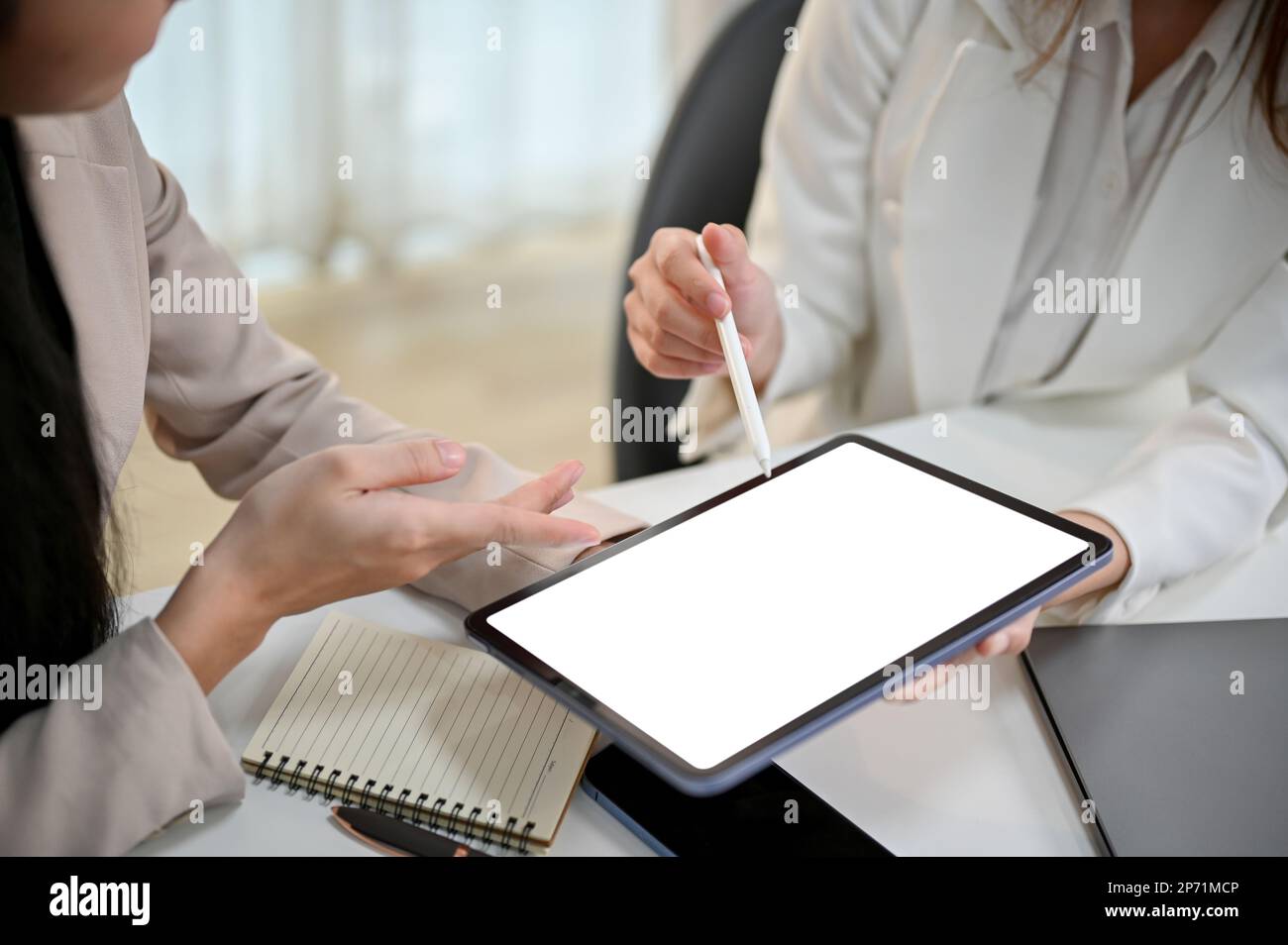 Close-up image of two millennial Asian female office workers discussing ...
