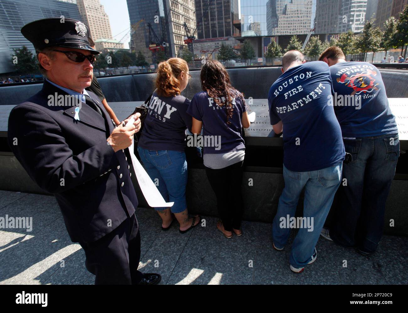 Visitors make etchings of the names of victims inscribed on the wall ...