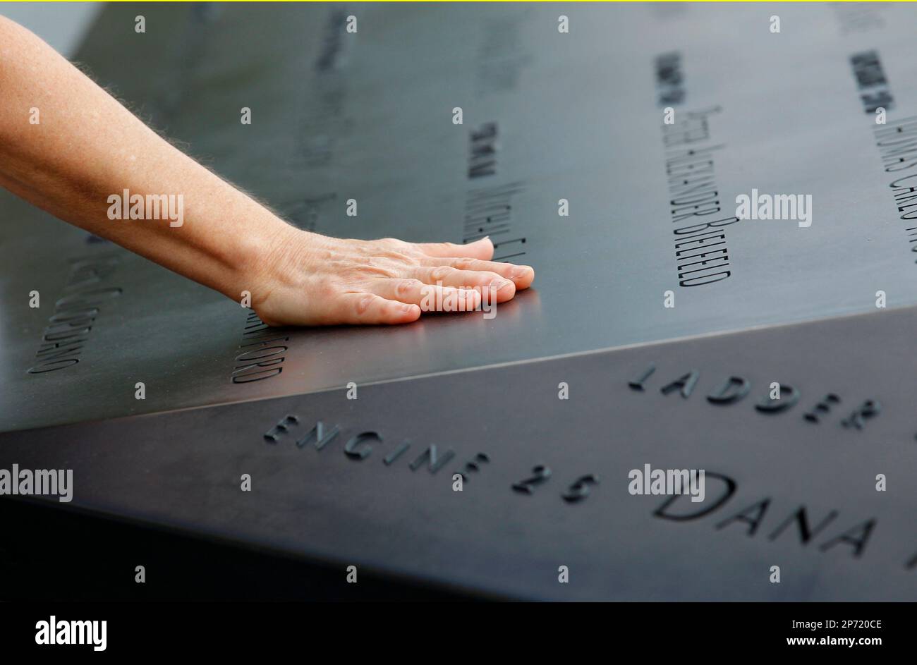 A woman places her hand on a name etched in the wall of one of the ...