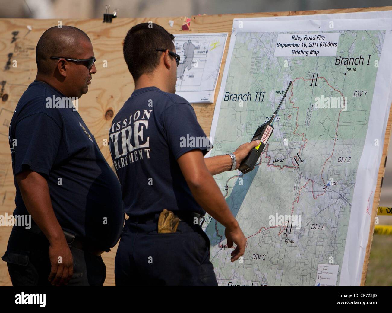 Firefighters review a map of the Riley Road wildfire at a command ...
