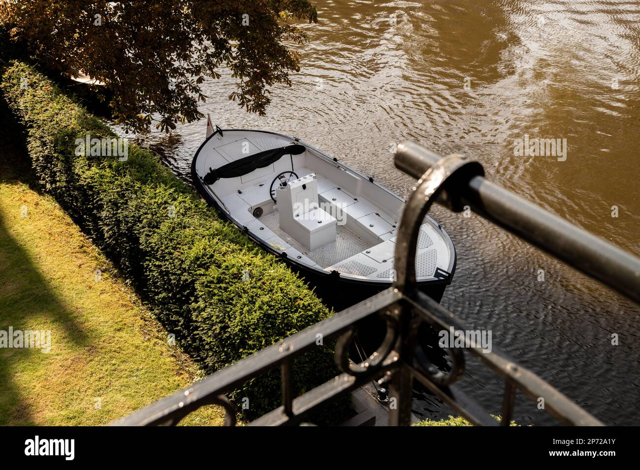 a small boat on the side of a river with trees and bushes in the fore ...