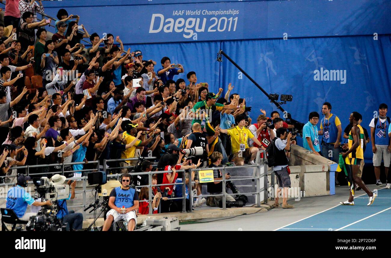 Spectators take photos of Jamaica's Usain Bolt, right bottom, during a ...