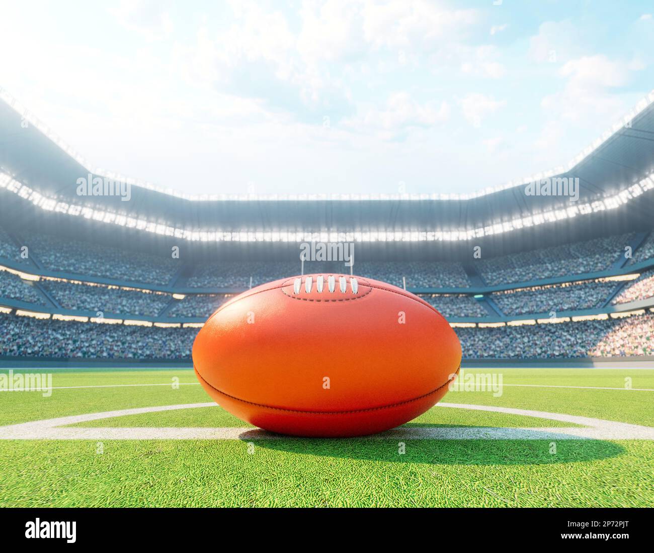 A red aussie rules ball on the center line of a stadium with posts on a ...