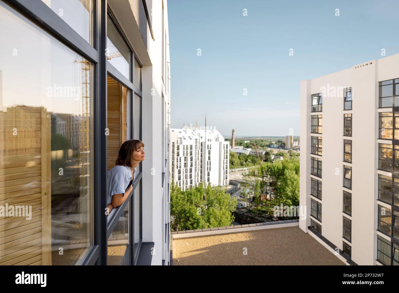 Woman looks out the window of apartment building Stock Photo - Alamy