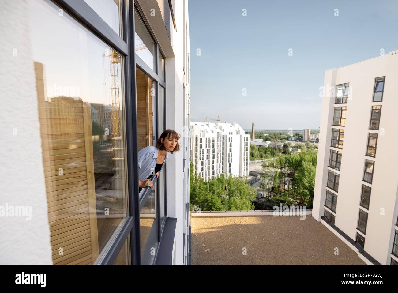 Woman looks out the window of apartment building Stock Photo - Alamy