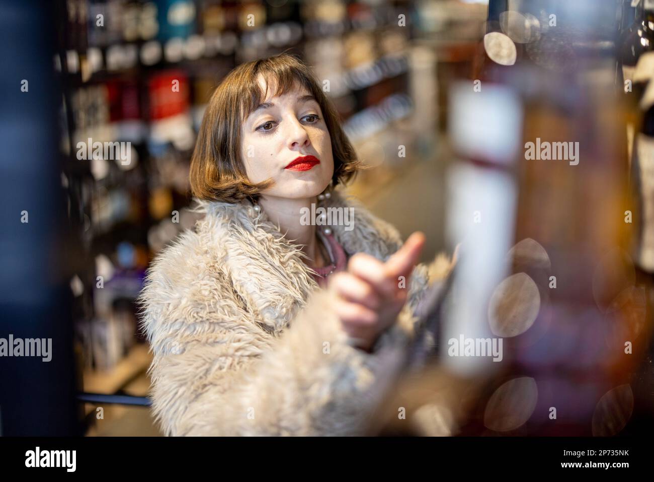 Woman chooses strong alcohol in supermarket Stock Photo - Alamy