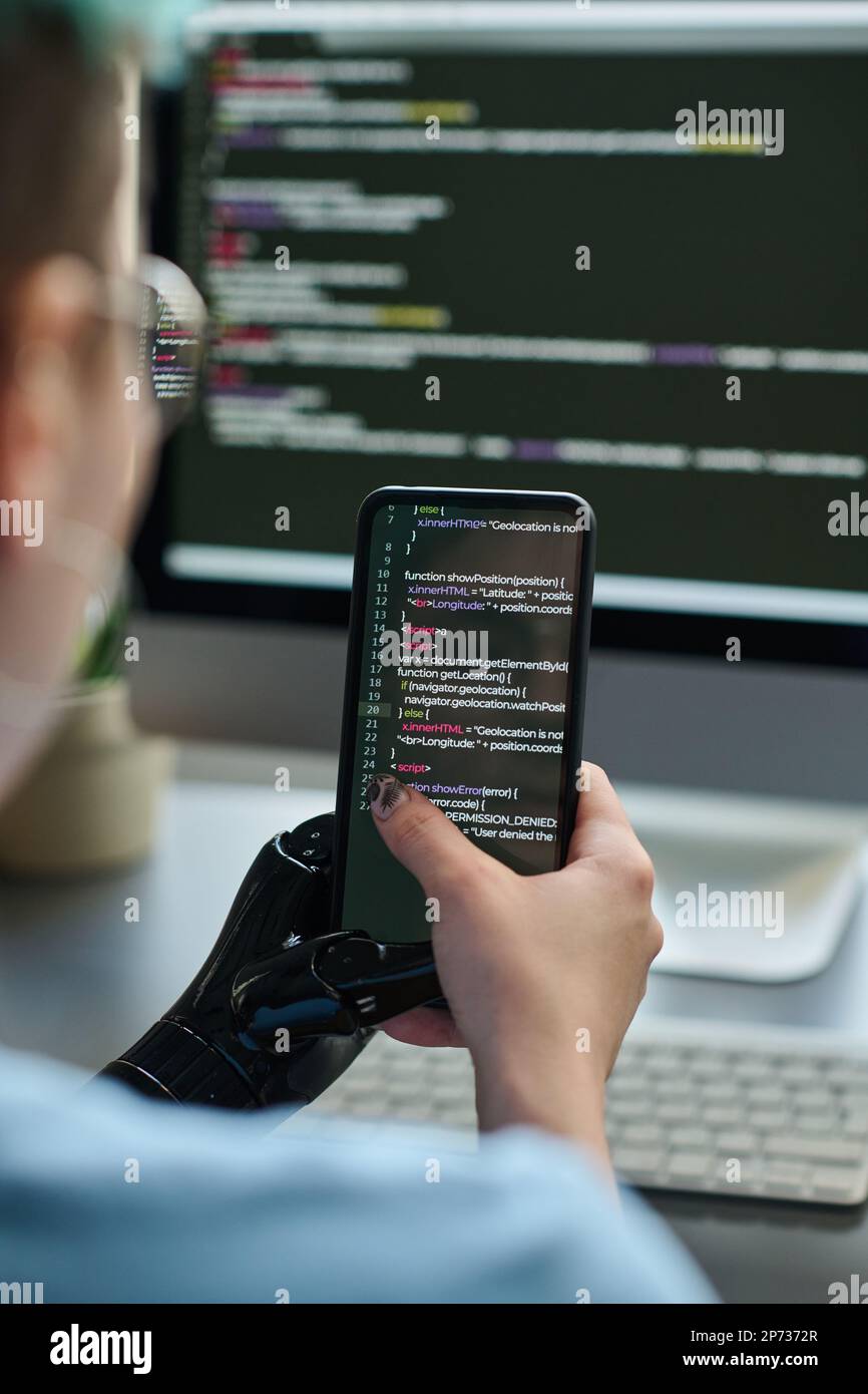 Vertical image of girl with prosthetic hand typing program codes on ...