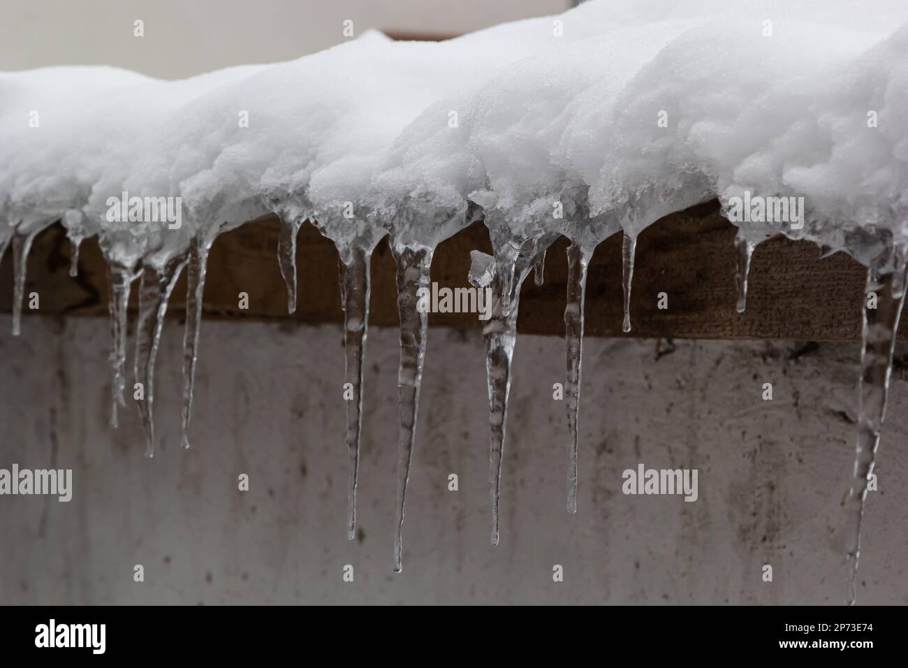 Sharp icicles and melted snow hanging from eaves of roof. Beautiful ...