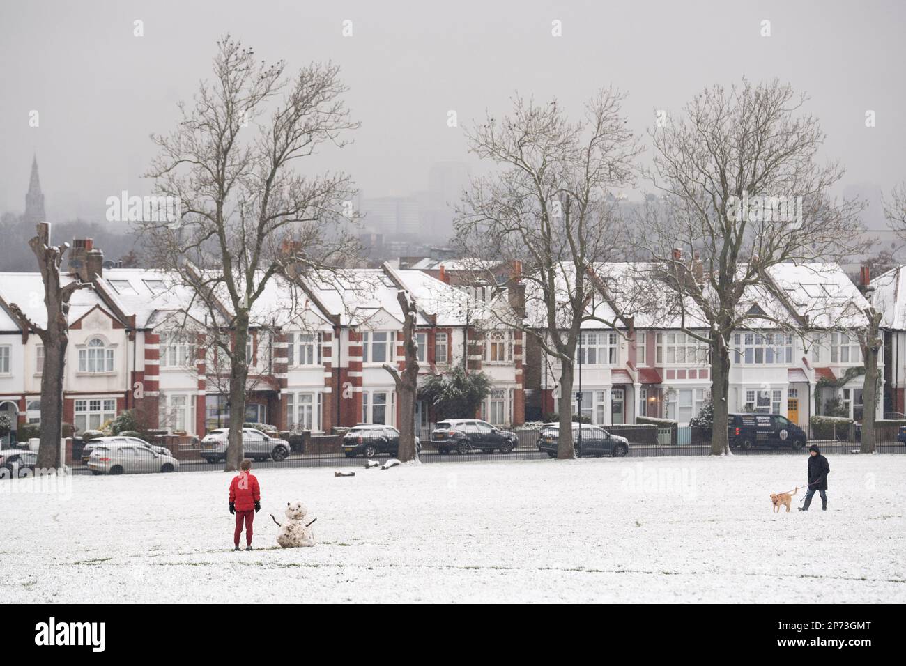 As March snow falls on south London, a boy builds a small snowman in ...