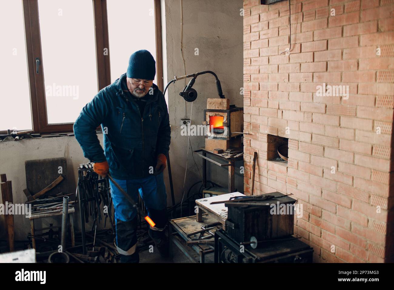 Blacksmith forge oven with hot flame. Smith put in and heating iron ...