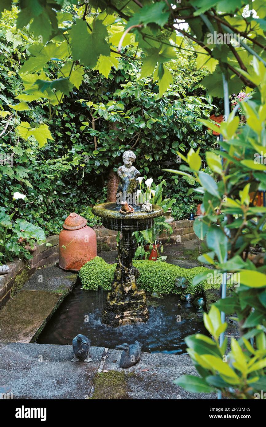 Attractive water feature with stone statue of small Stock Photo - Alamy