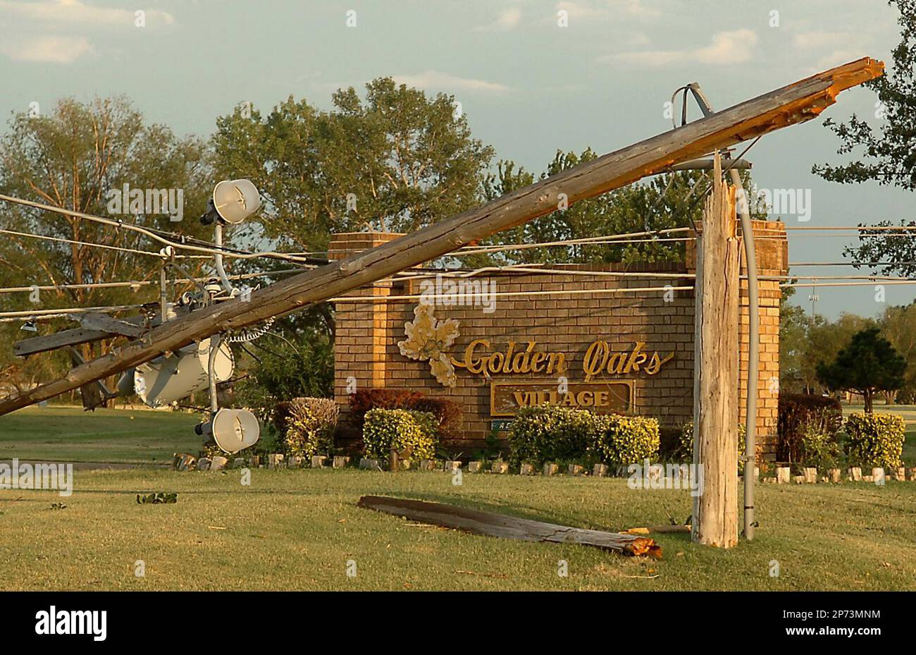 A snapped utility pole frames the Golden Oaks entrance sign after a ...