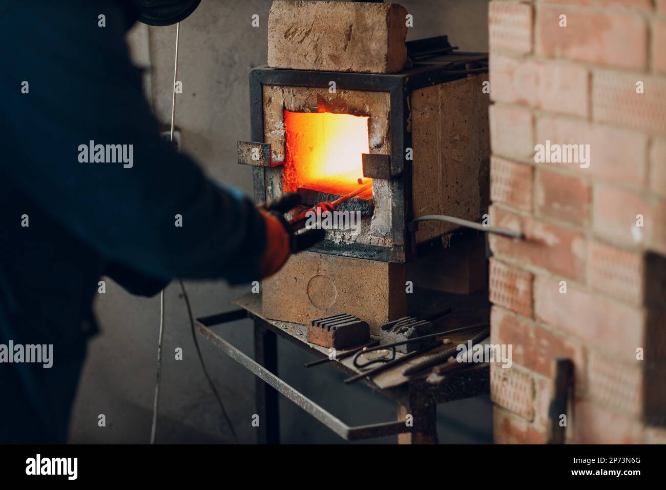 Blacksmith forge oven with hot flame. Smith heating iron piece of steel ...