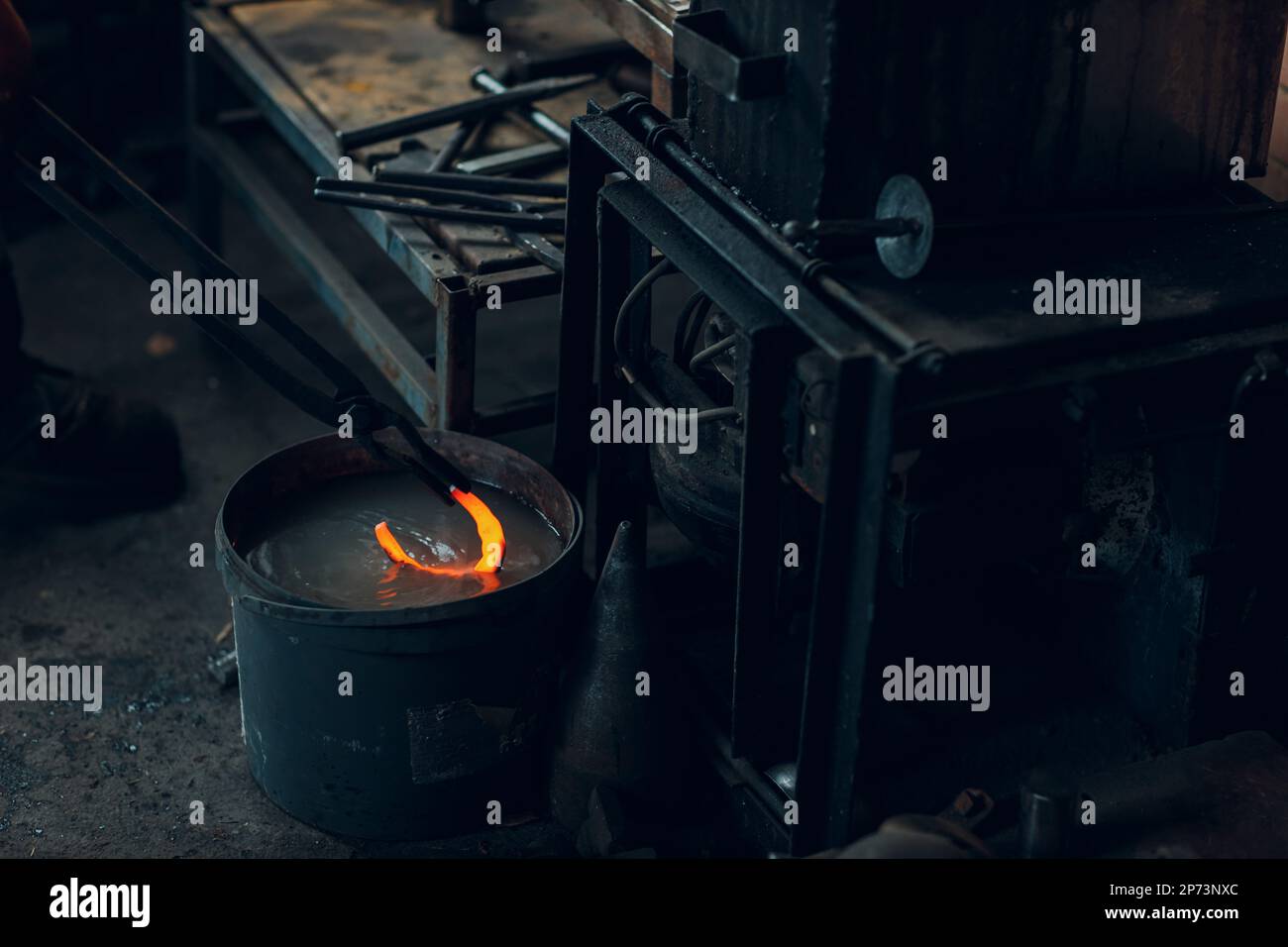 Blacksmith forges and tempering metal horseshoe in jar with water at ...