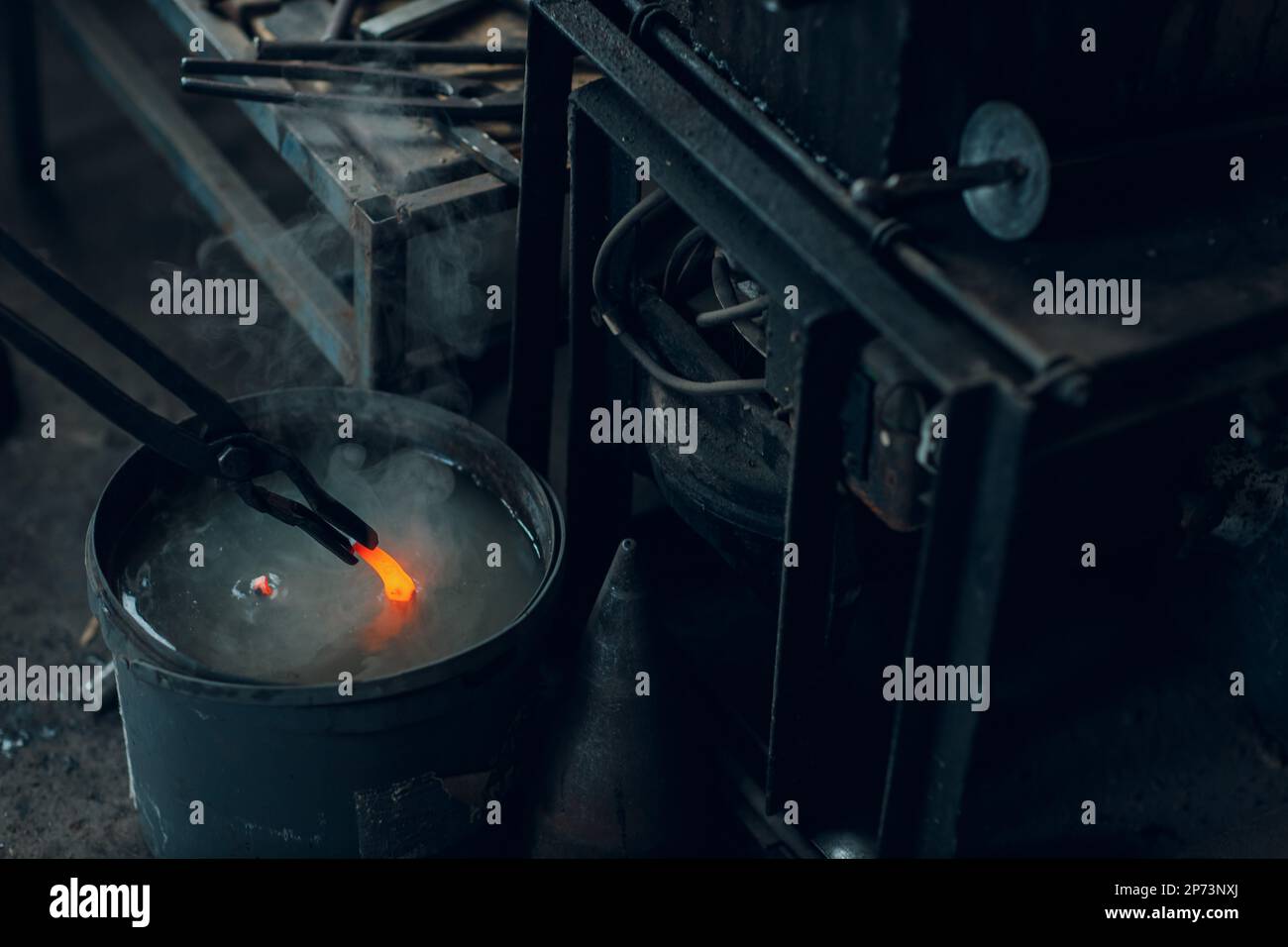 Blacksmith forges and tempering metal horseshoe in jar with water at ...